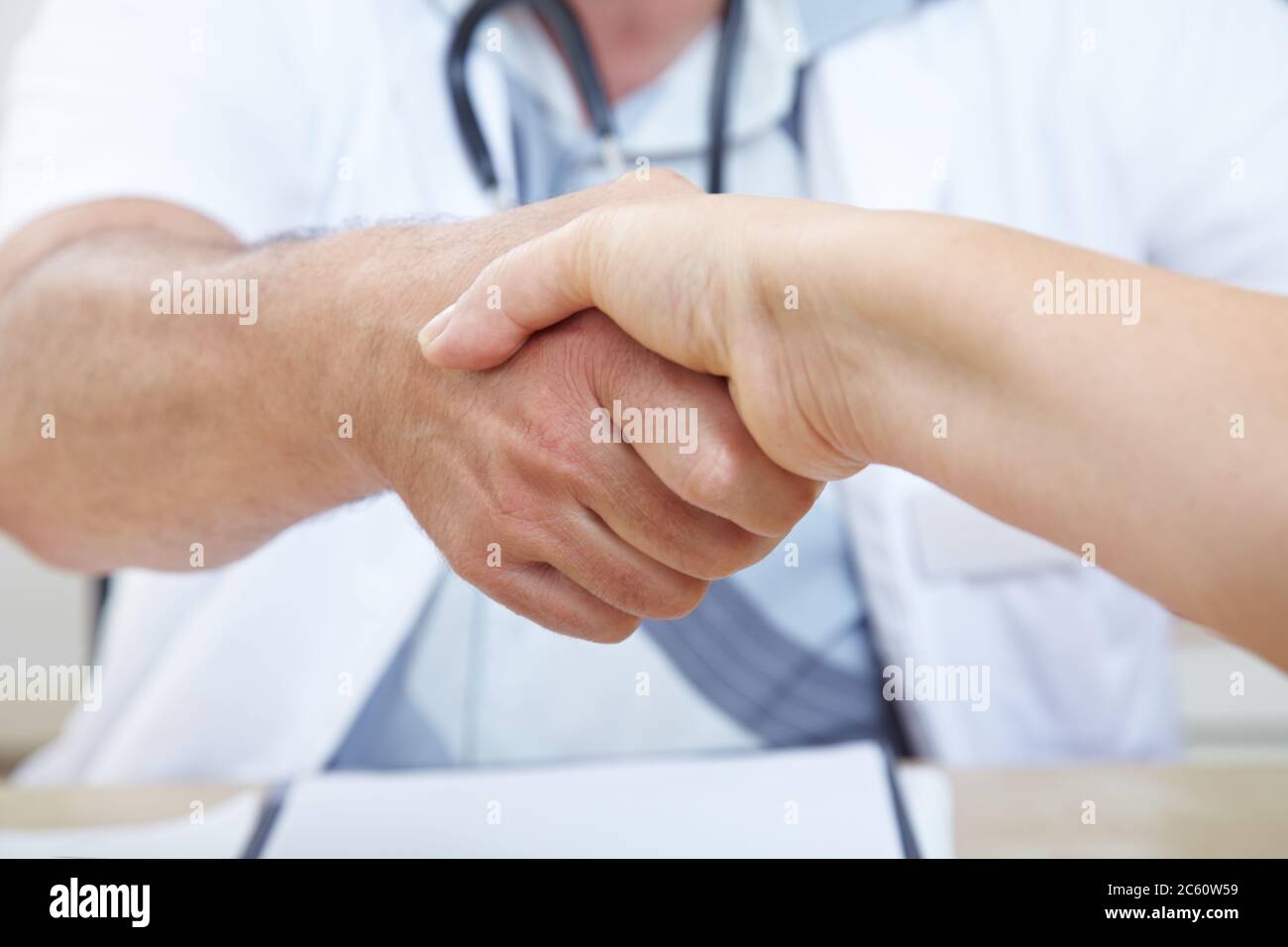 Handshake between a doctor and a patient across the table Stock Photo ...