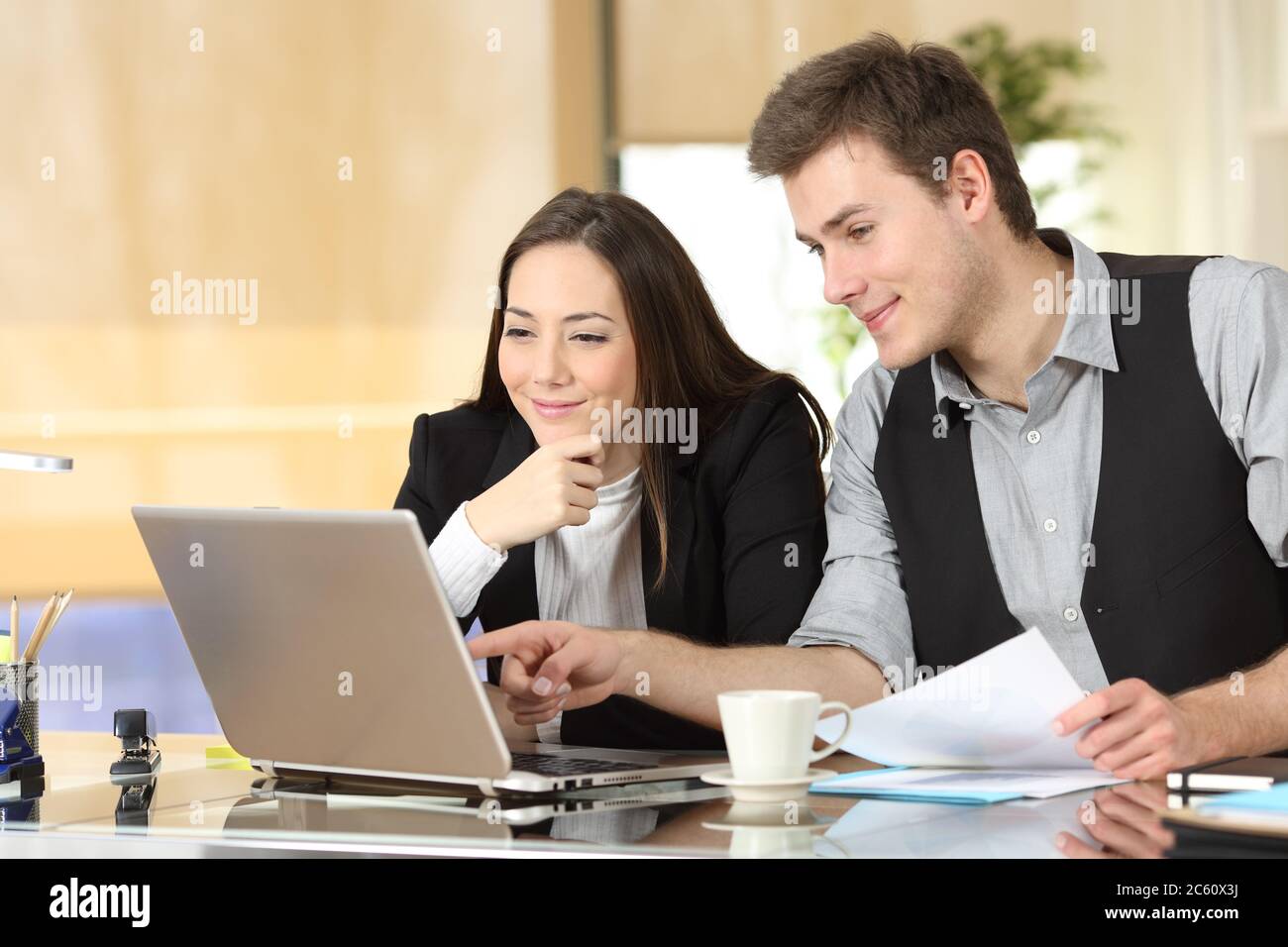 Satisfied office workers checking laptop online content at office Stock ...