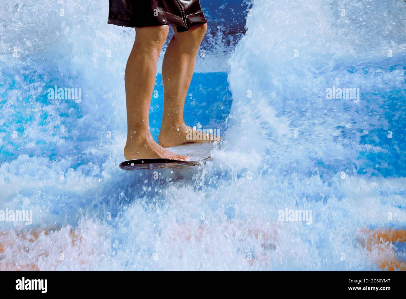 Man take wake surf, riding a surfboard or foot board along an outdoor ...