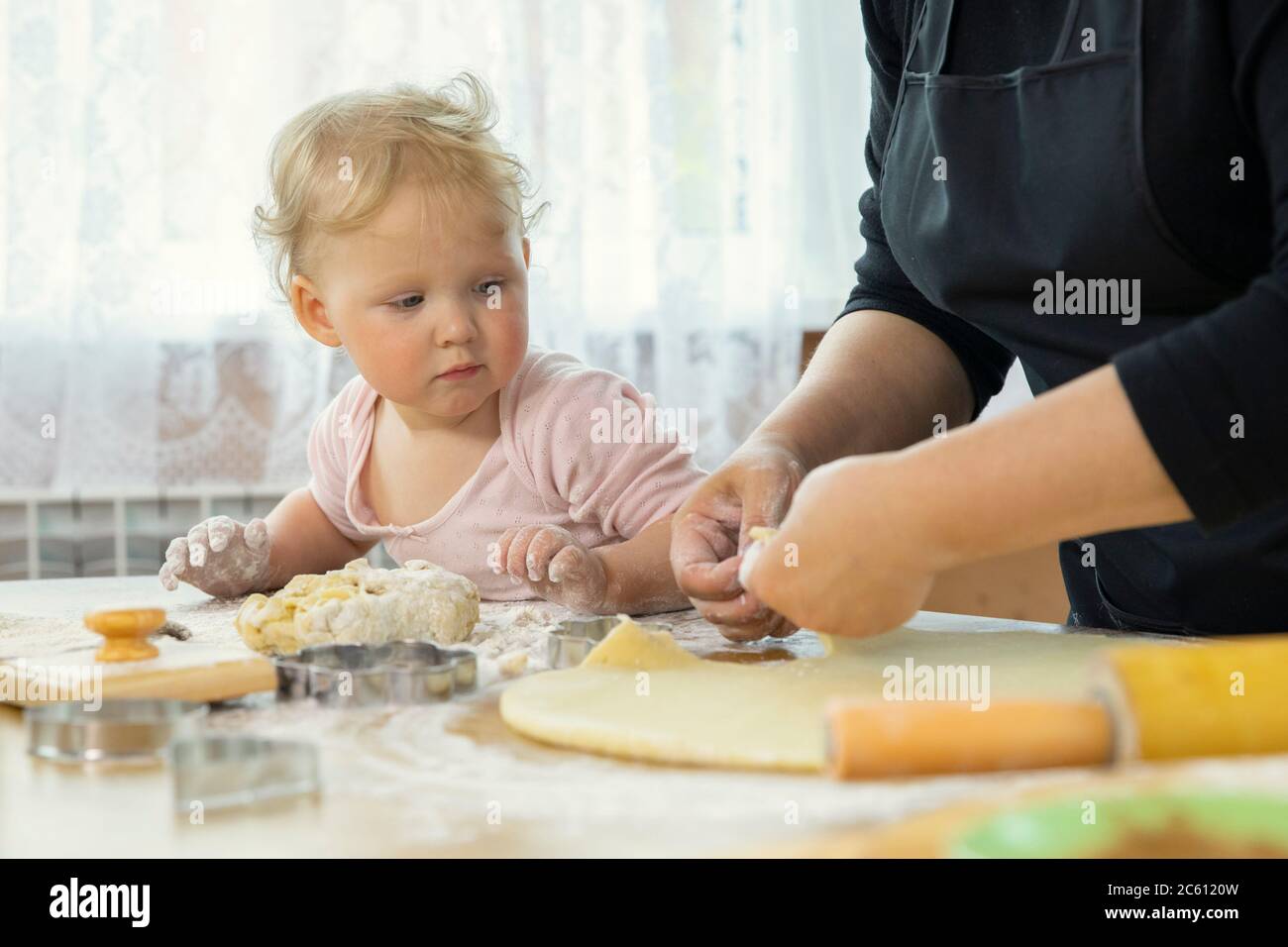 Little cute baby and grandma cooking on kitchen, child in flour ...