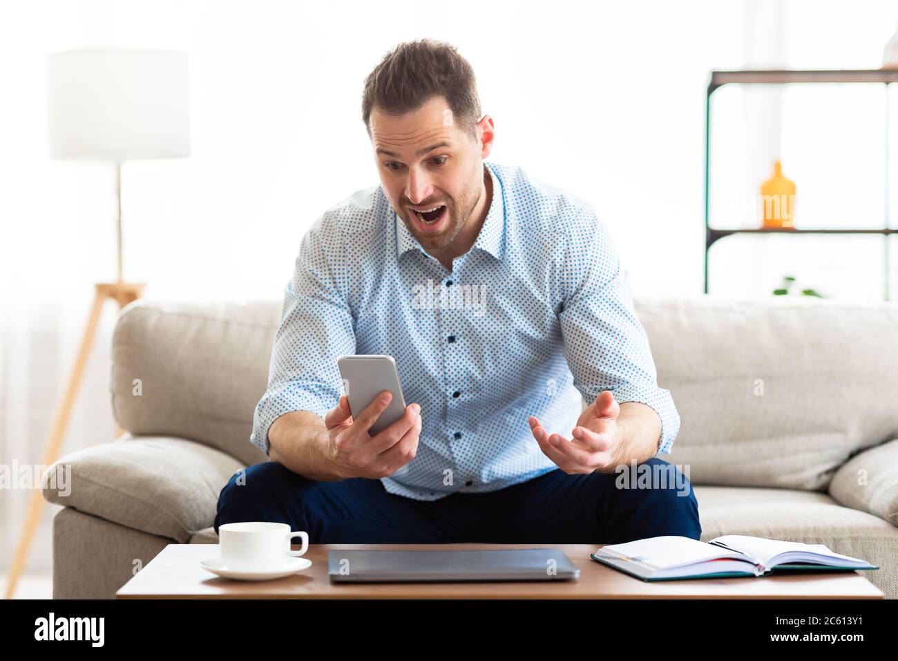 Angry man screaming at mobile phone at home Stock Photo - Alamy