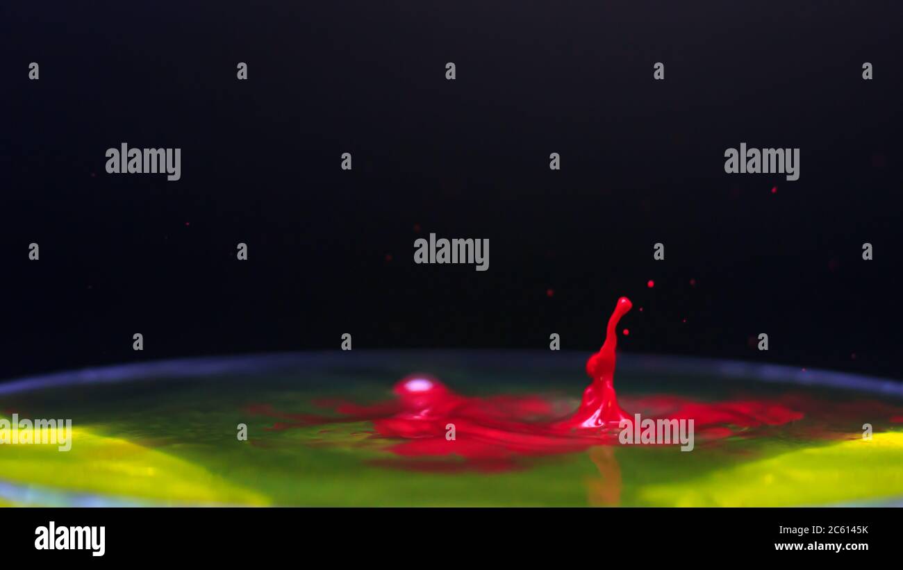 Red color drop falling in green color water Stock Photo - Alamy