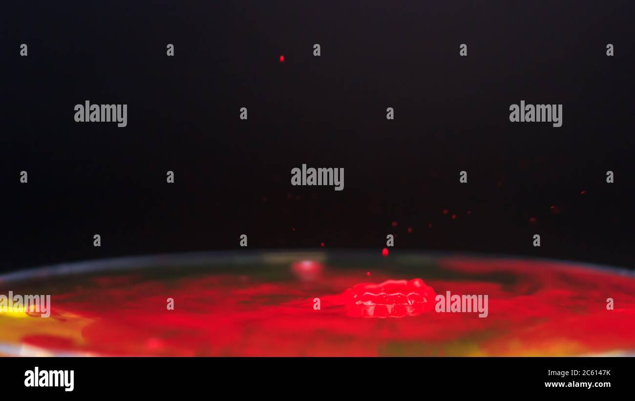 Red color drop falling in green color water Stock Photo - Alamy