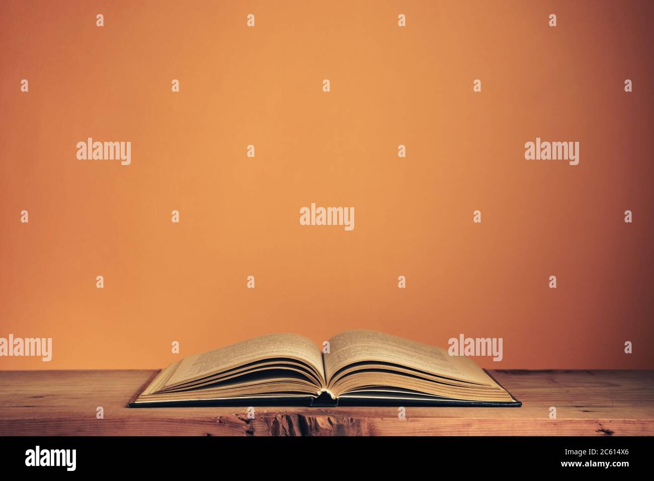 Beautiful ancient open old book on a red wooden table and orange wall ...