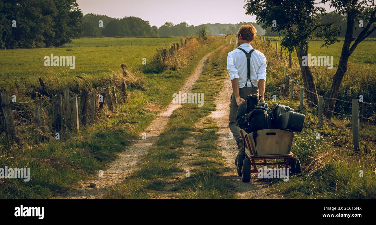Musician with handcart, loaded with instruments, walking on a romantic ...