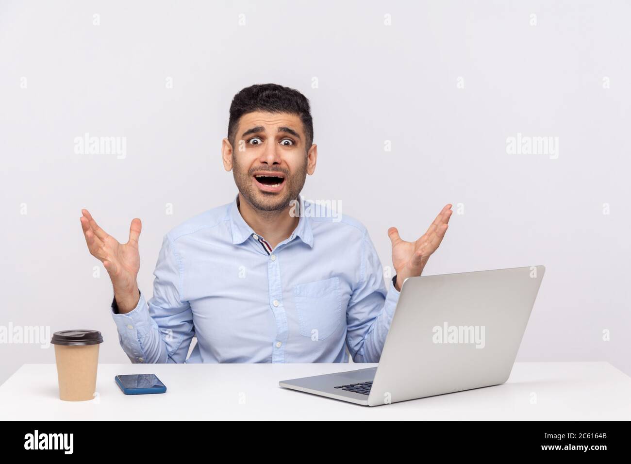 Scared shocked man employee sitting in office workplace with laptop and ...