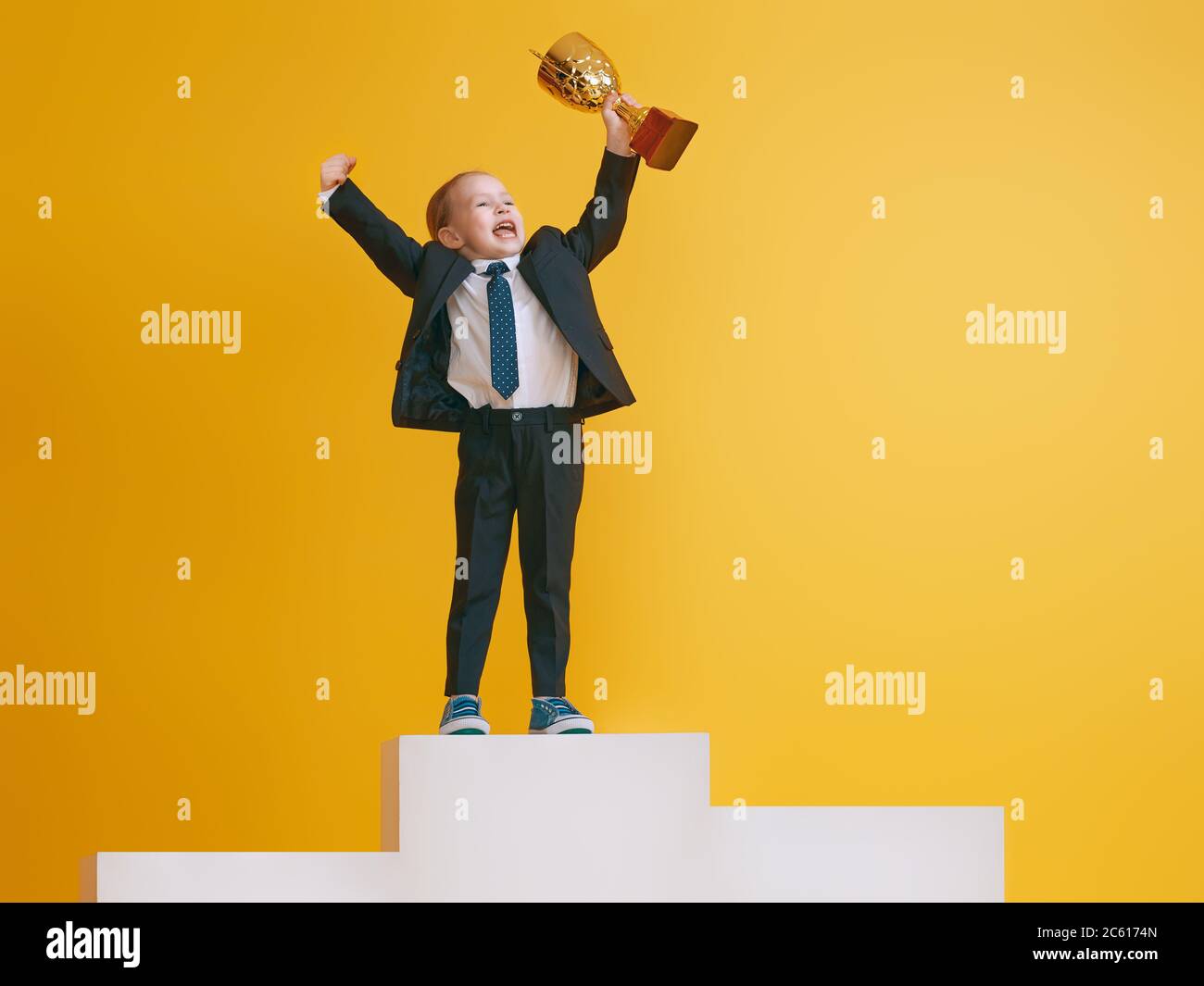 Little child is winner. Kid on the background of bright yellow wall ...