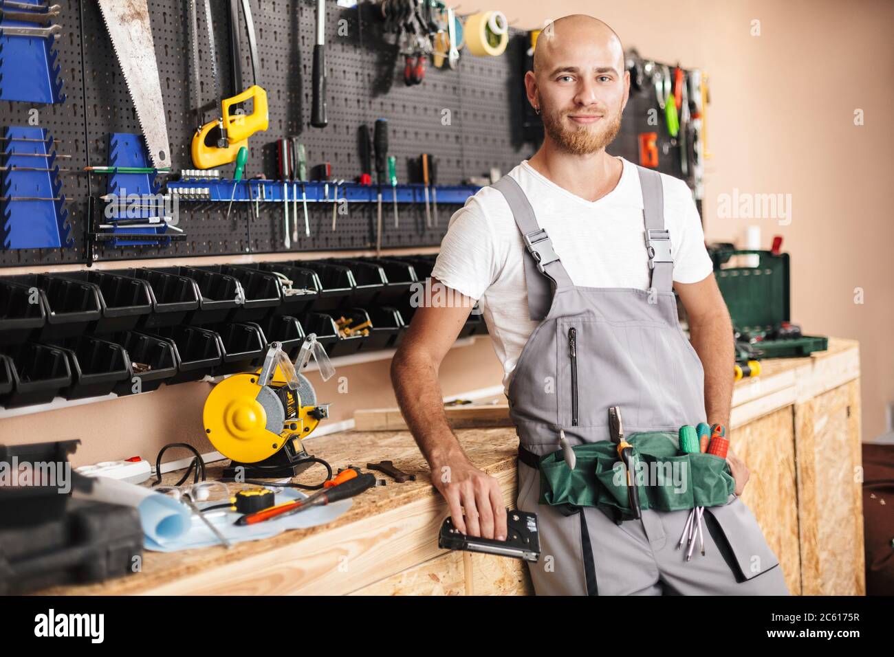 Smiling foreman in work clothes holding stapler in hand dreamily Stock ...