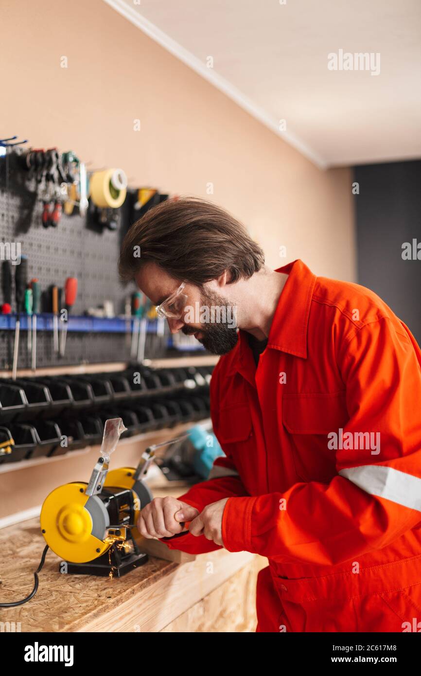 Foreman in orange work clothes and protective eyewear working wi Stock ...