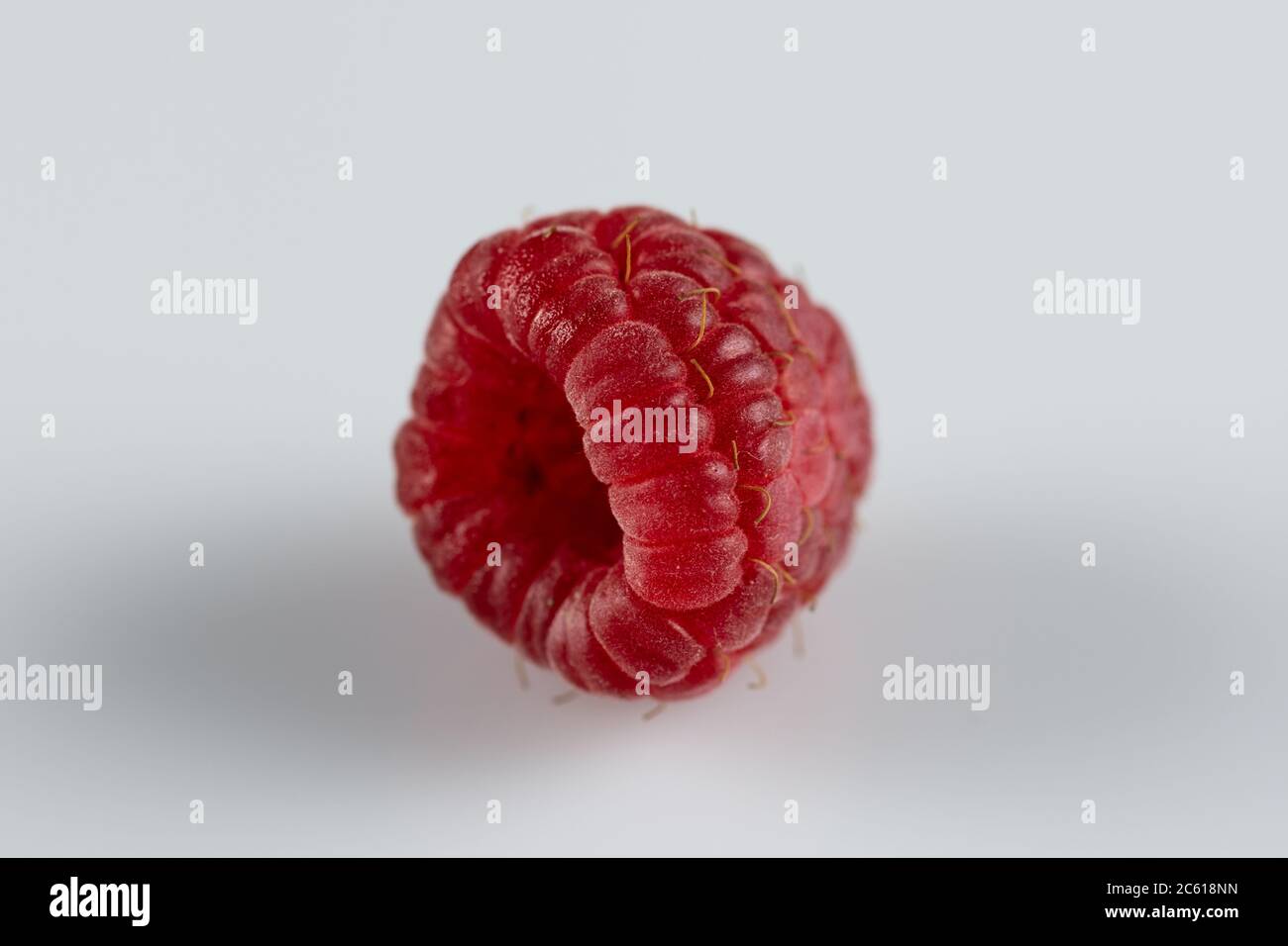 Single red raspberry with light background Stock Photo - Alamy