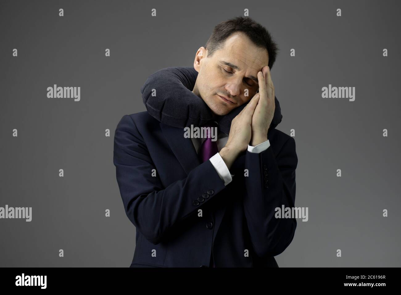 man asleep standing up with hands under head inflatable pillow around ...
