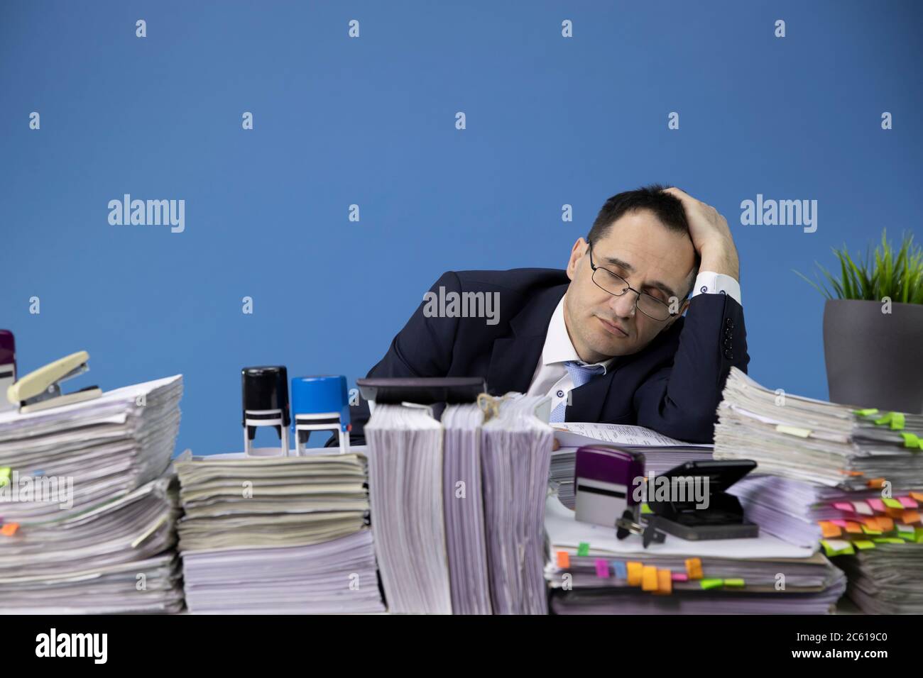 overwhelmed overworked businessman asleep at office desk loaded of ...