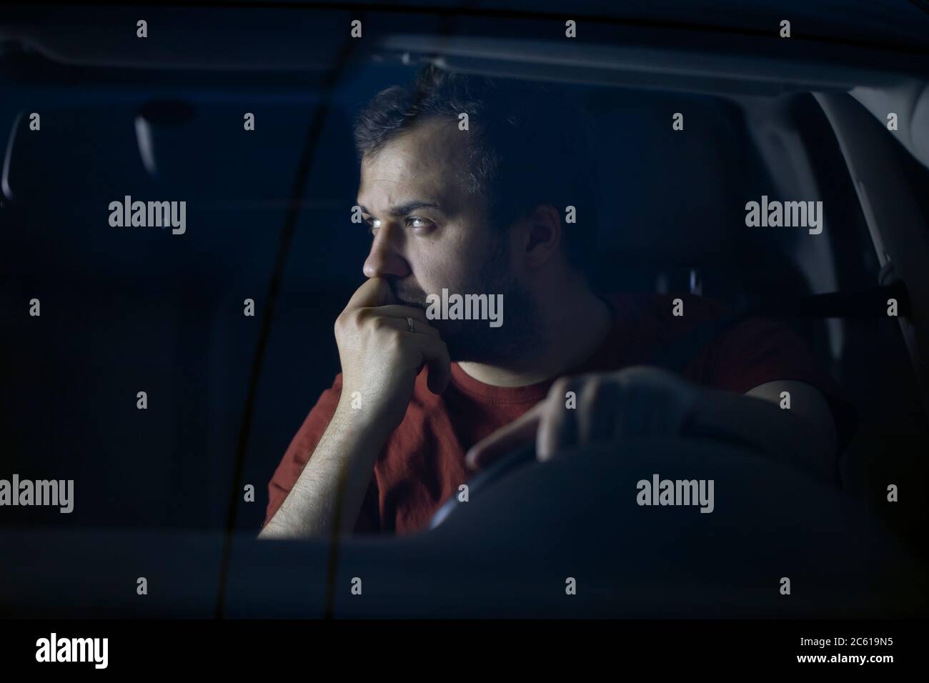 Sad man driver sits at steering wheel of car at night thoughtfully ...