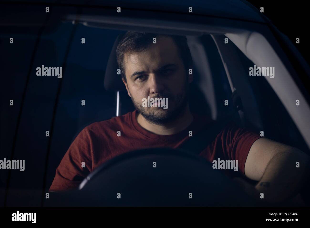 sad man driver sits at steering wheel of car at night thoughtfully ...