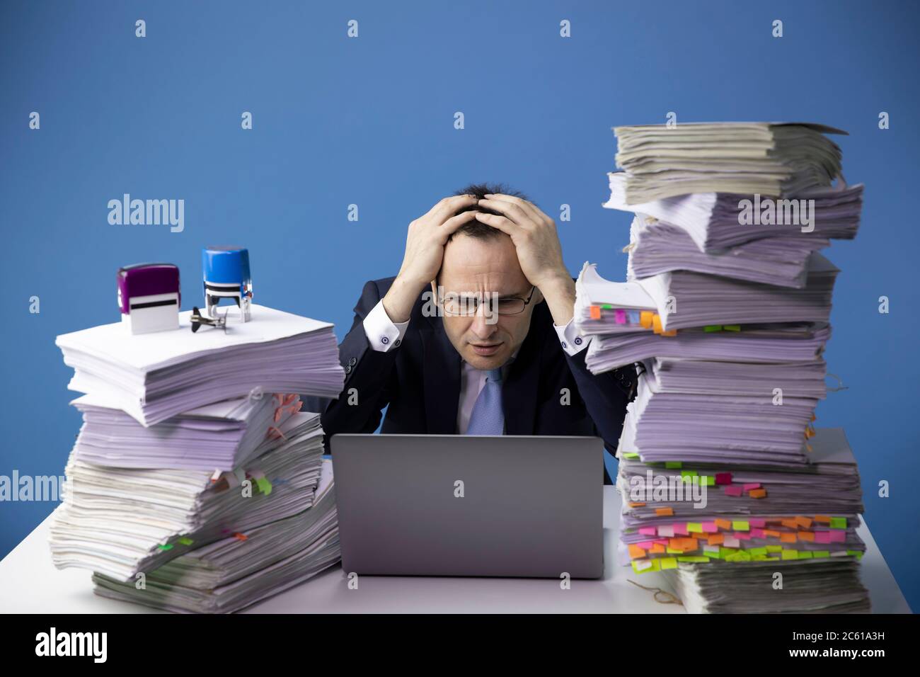 exhausted office employee doing overtime project amidst high stacks of ...