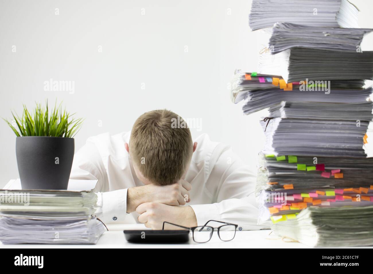 overworked businessman laid his head down on desk loaded of paperwork ...