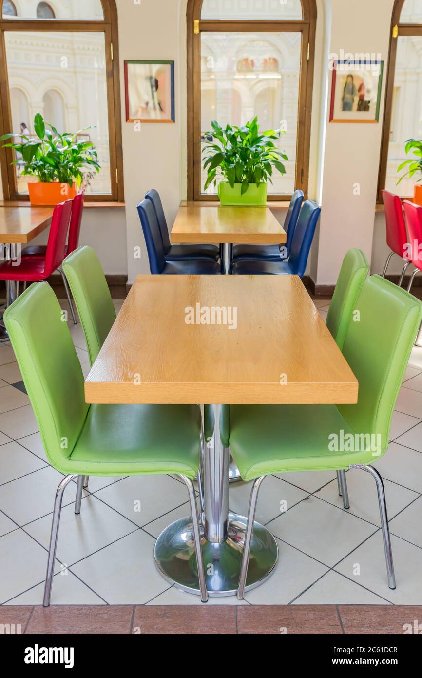 interior of the cafe - wooden tables and multicolored leather chairs ...