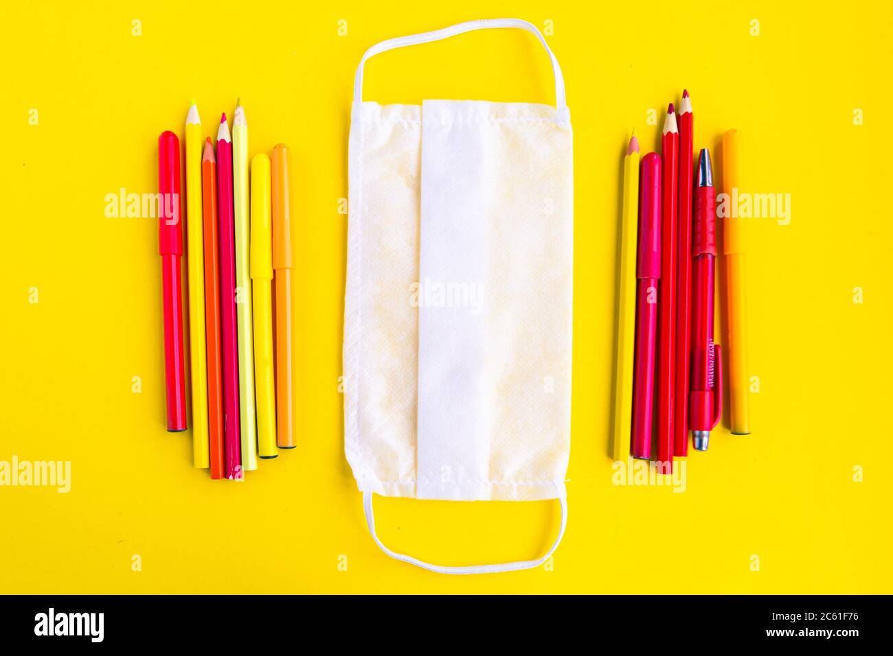 Color pencils and medical mask on yellow background, top view. Back to ...