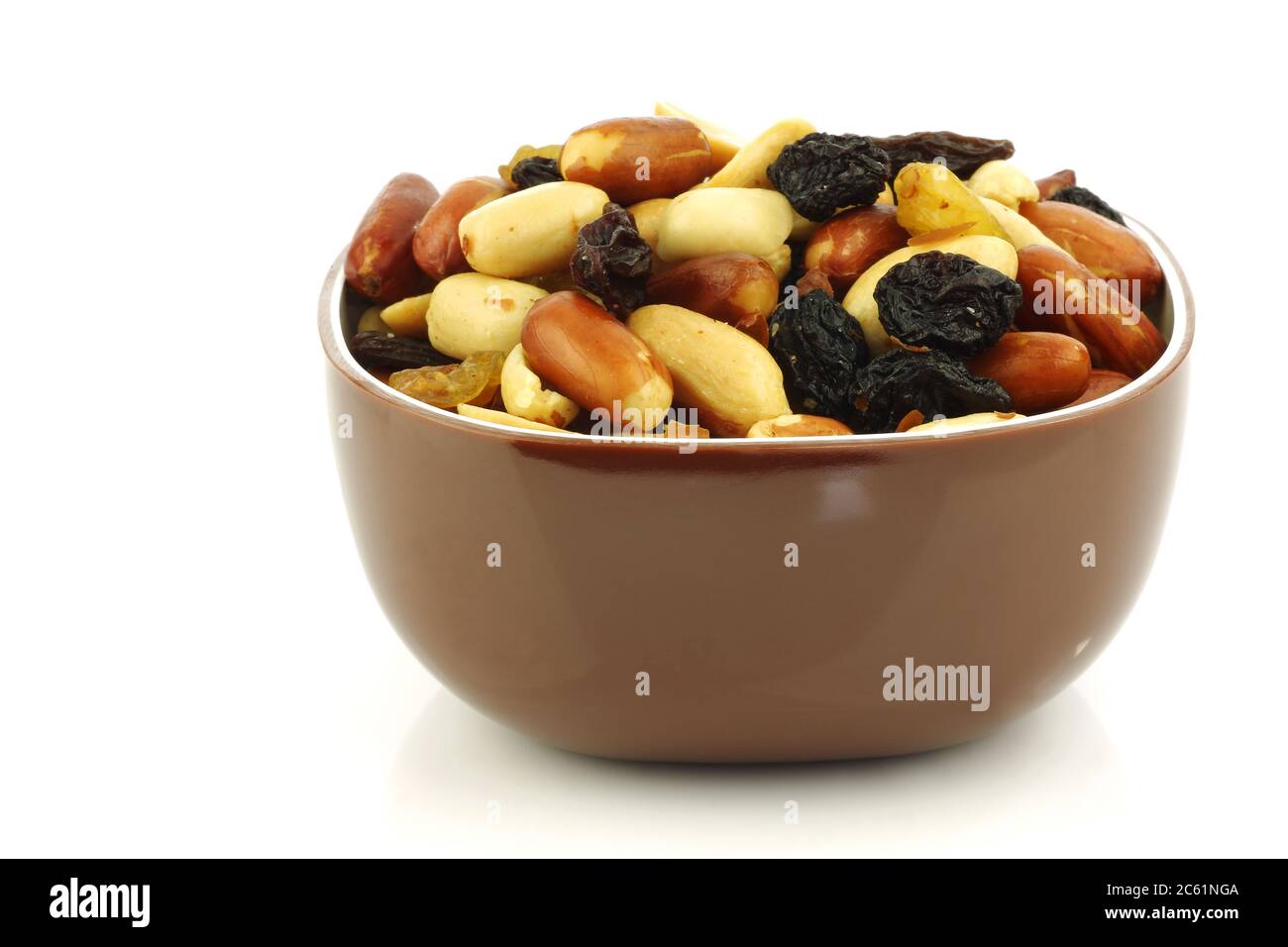 mixed peanuts and raisins in a brown bowl on a white background Stock ...