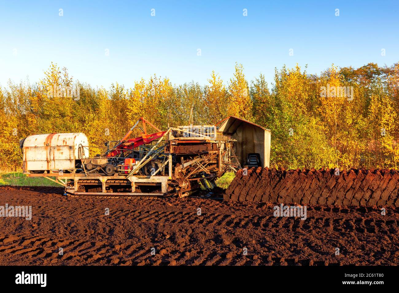 An excavator cuts peat and piles it in rows in a bog in Northwestern ...