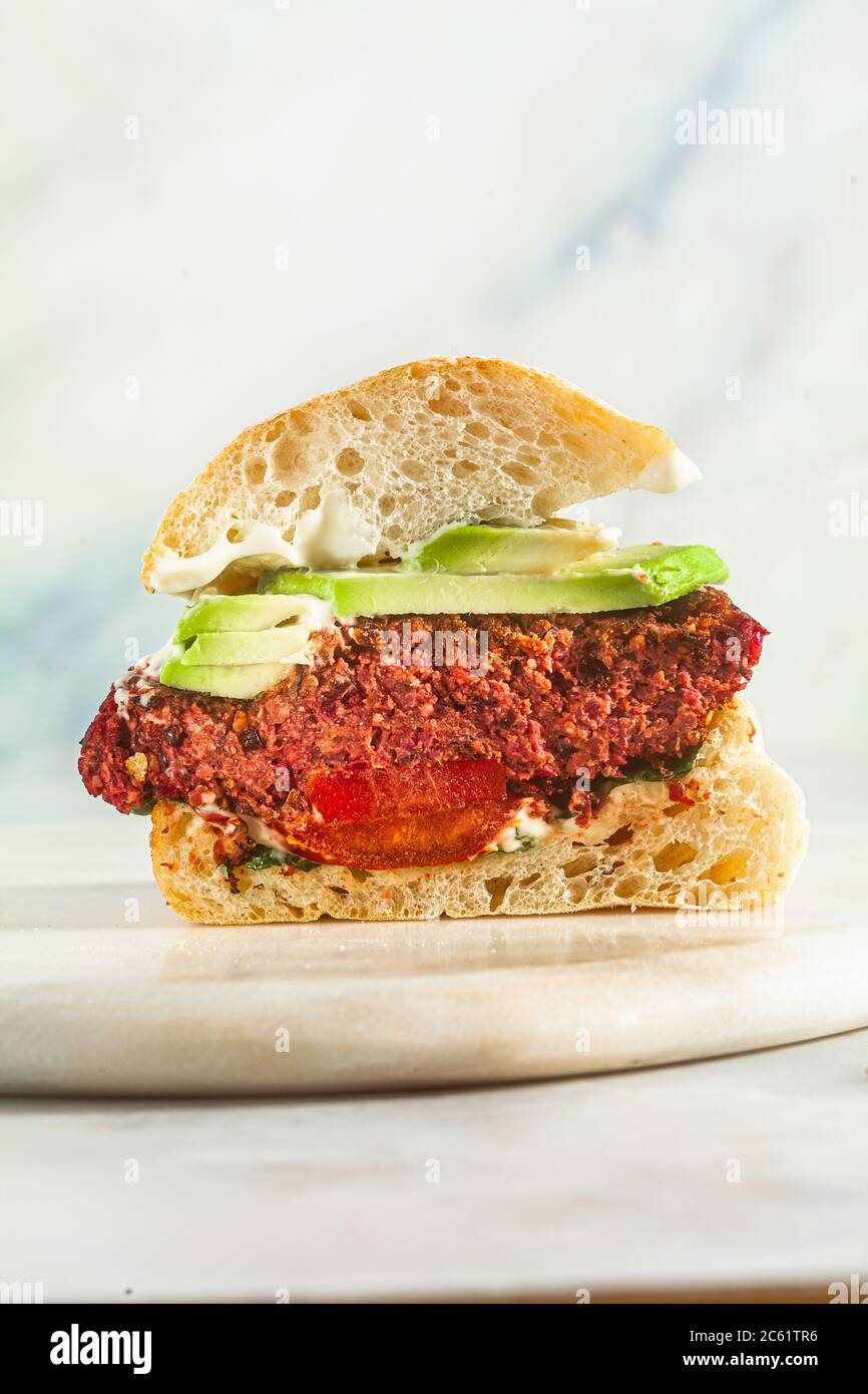 cut vegan burger without meat with avocado, tomatoes and spinach on the ...