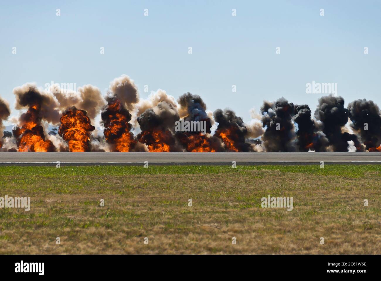 Multiple firey explosions with thick black smoke on an airport runway ...
