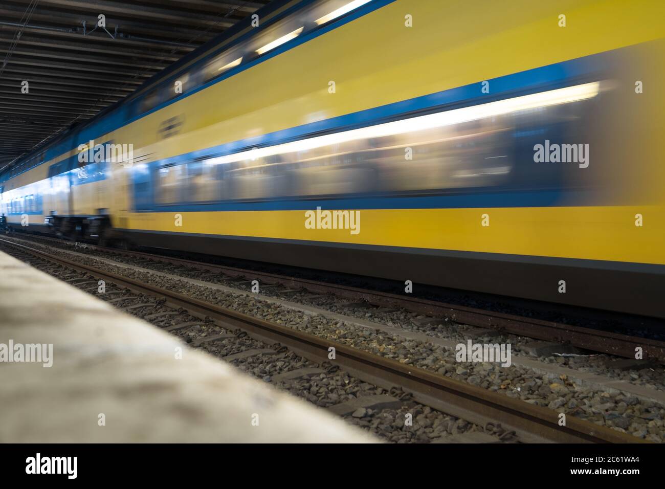Dutch train passing by on a railway in a station in the Netherlands ...