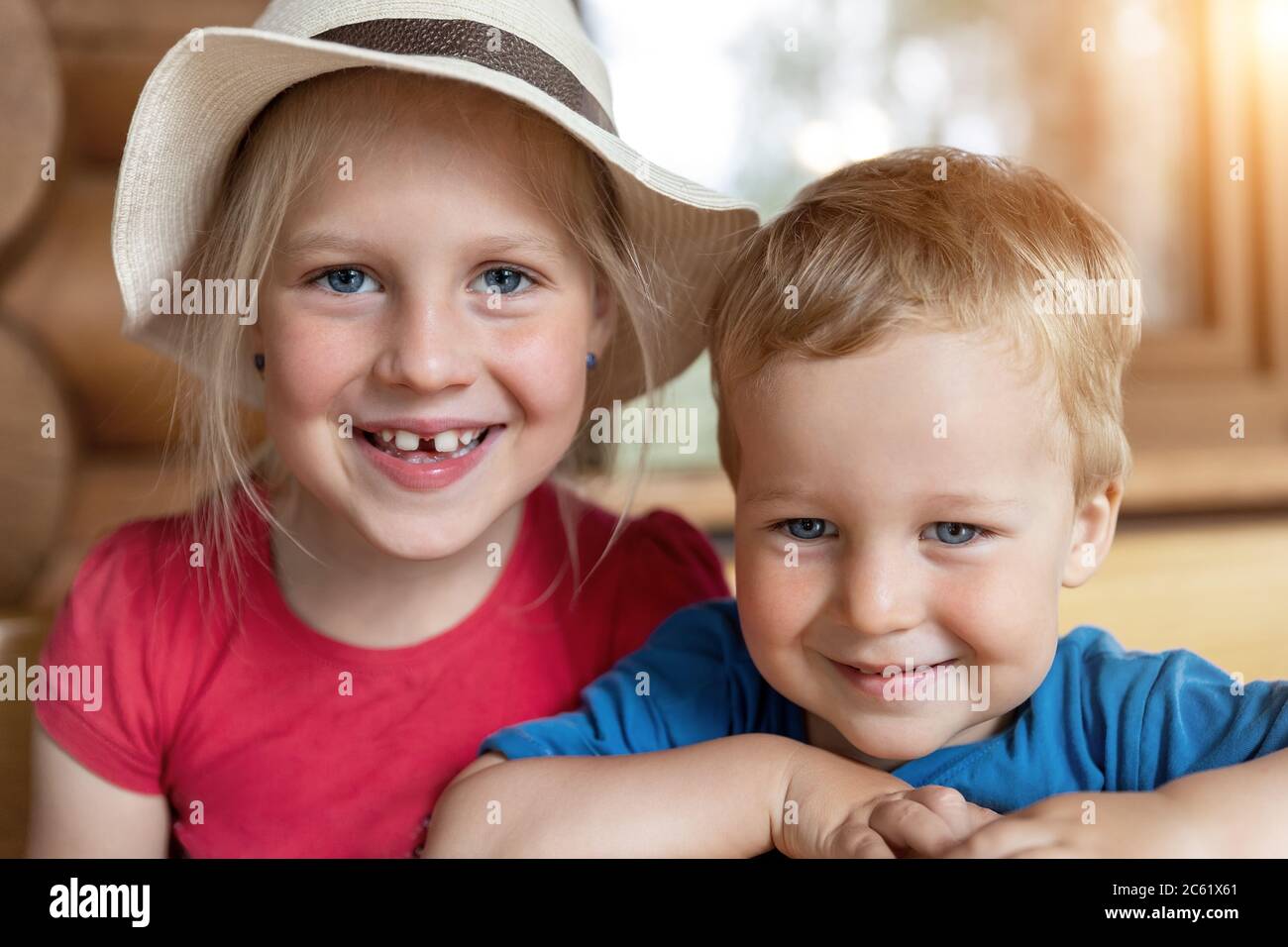 Two cute adorable caucasian blond little siblings sitting at table home ...