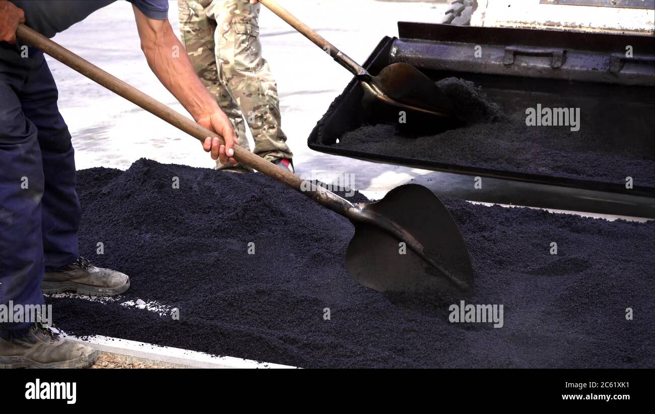Close-up,working men shoveling black gravel for laying asphalt on the ...