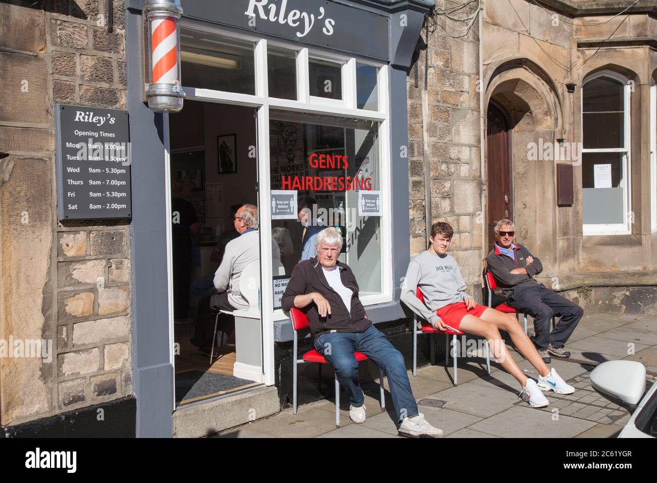 Barnard Castle,UK.6th July 2020. A group of men sit outside the barbers ...