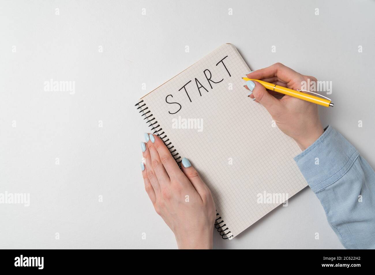 Start written on notebook over white background. Female hand writing in ...