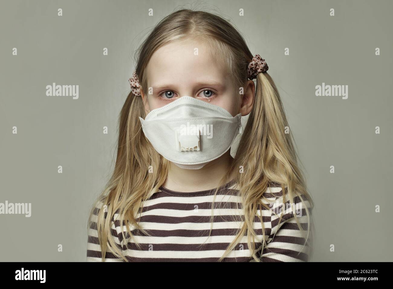 Child crying with tears wearing medical mask on gray background Stock ...