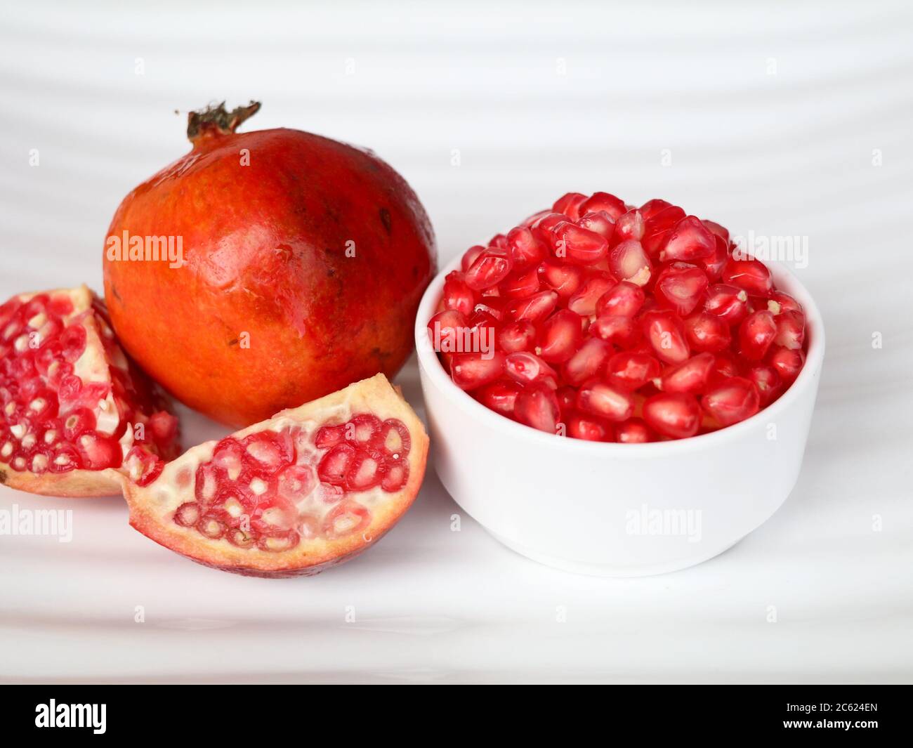 Fresh red color pomegranate fruit and kernels in a white background ...