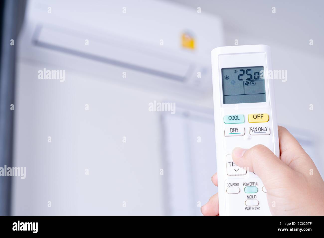 Human hand is using white remote of air conditioner for turn on or ...