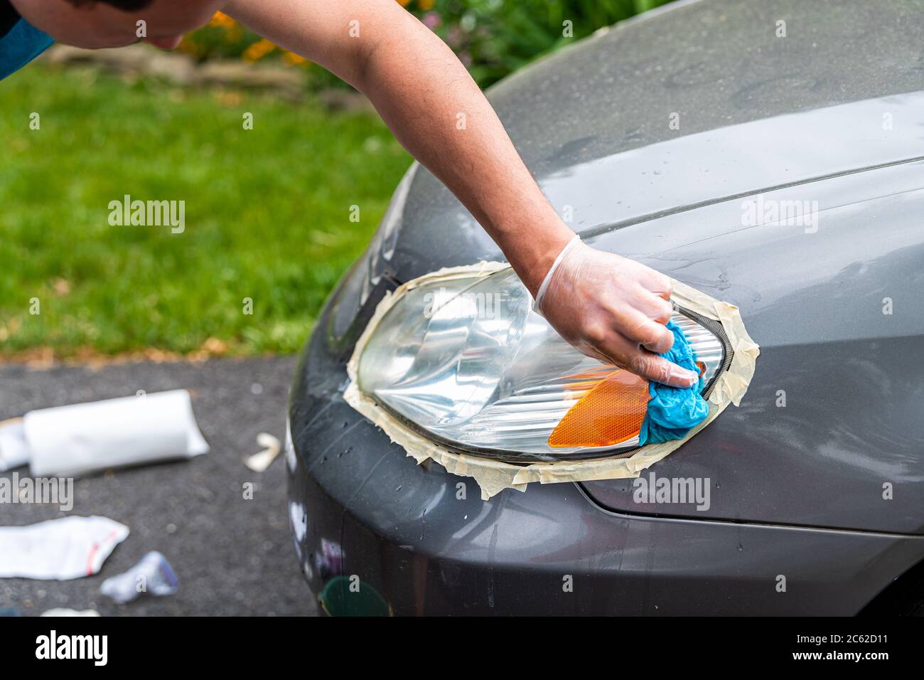 Man person worker cleaning car headlights taped to protect paint ...