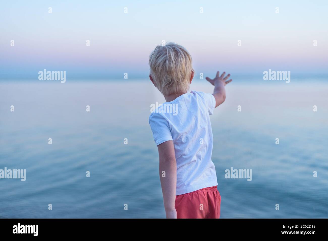 Child reaches out hand to sea. Blond boy on sea background Stock Photo ...