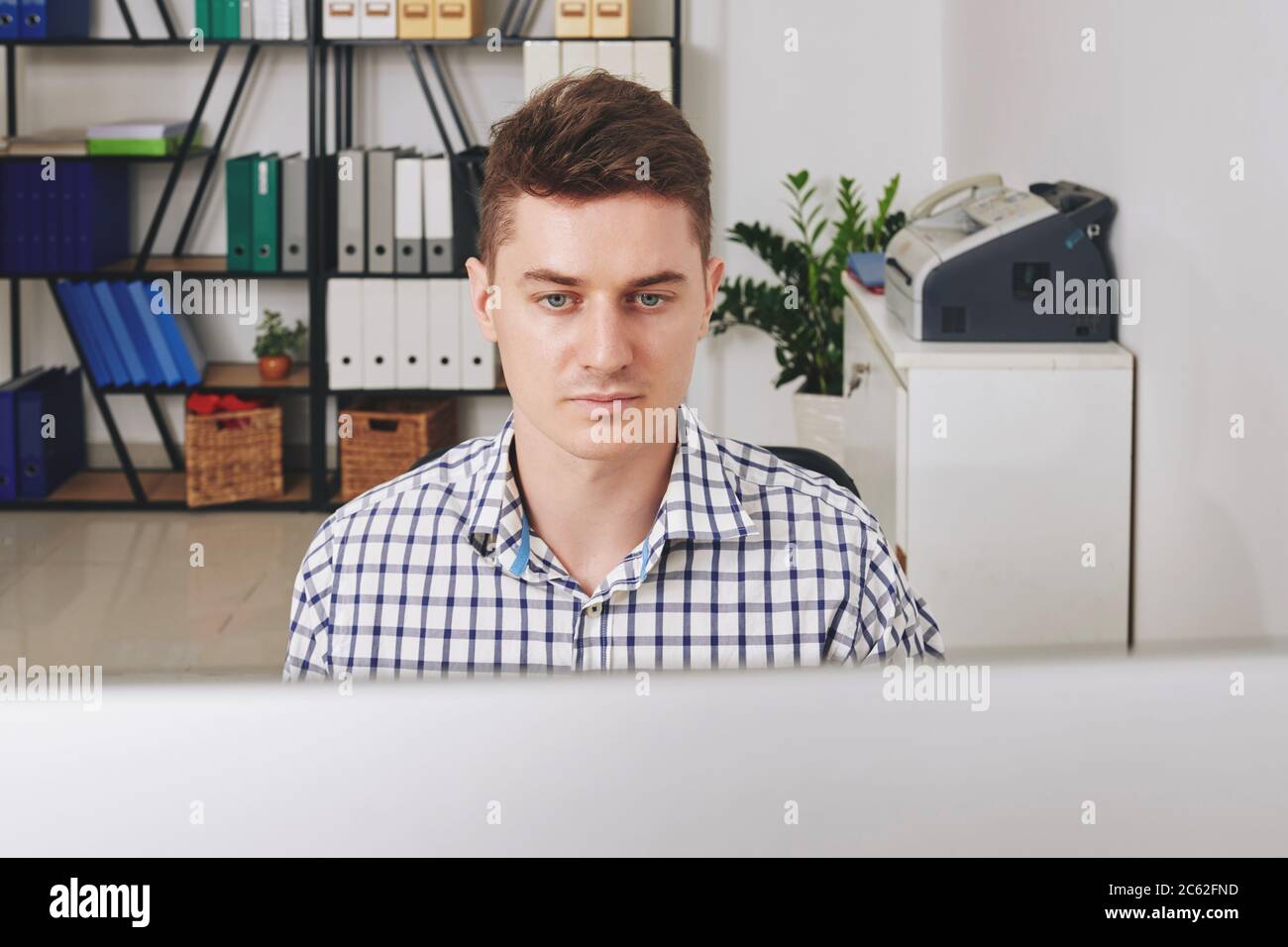 Serious young software developer working on computer in office Stock ...