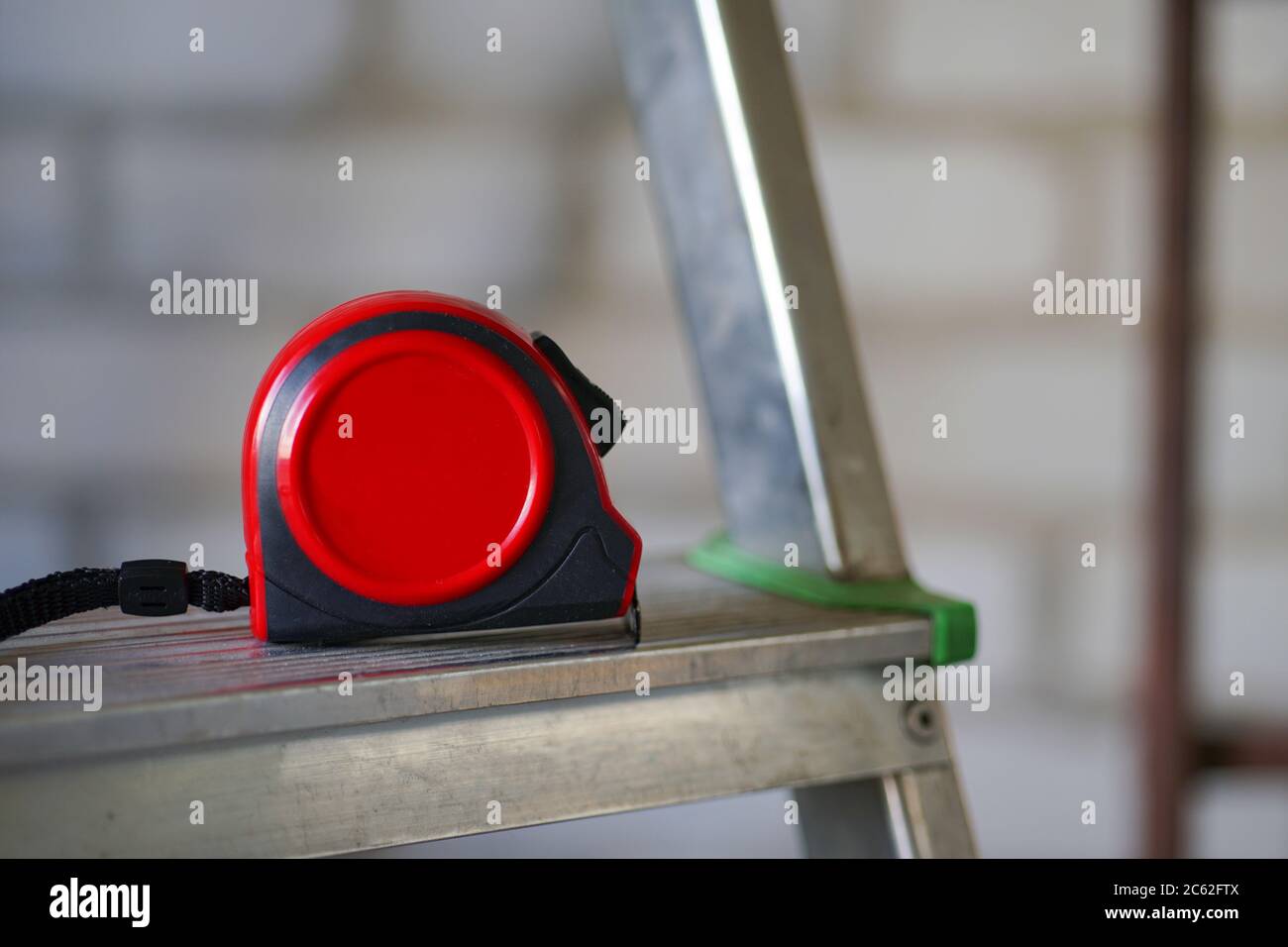 Red construction tape measure lies on the step of the ladder Stock ...