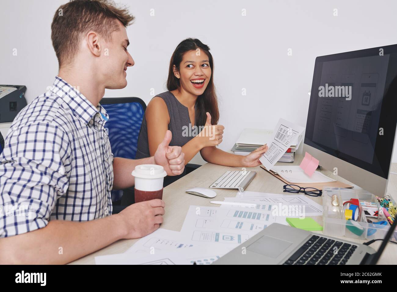 Happy excited young UI designer showing mobile application interface ...