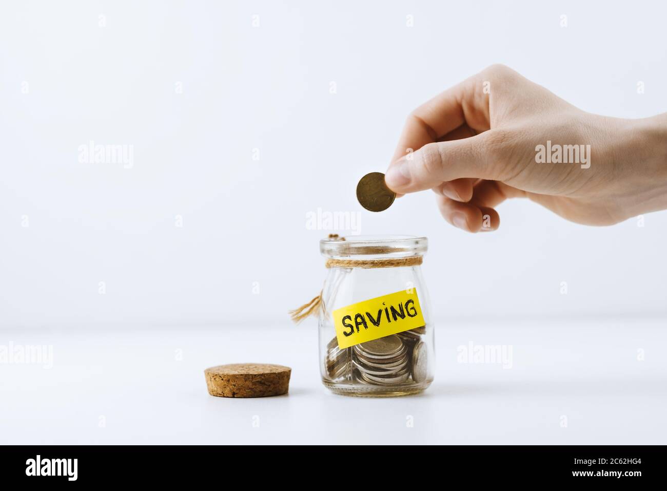 Female hand puts a coin in a jar Stock Photo - Alamy
