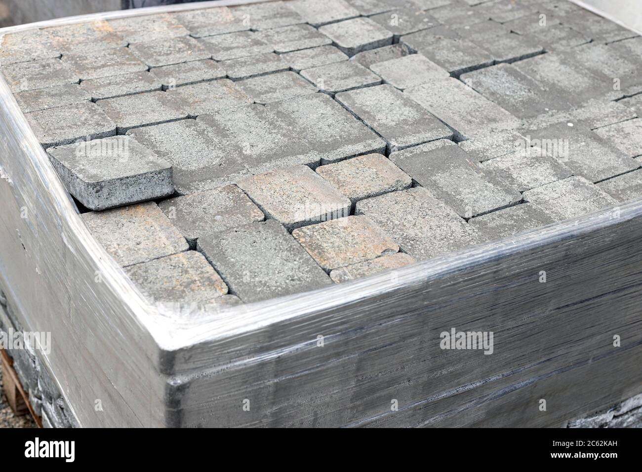 Pile of new grey paving stones on wooden pallet fixed with stretch wrap ...