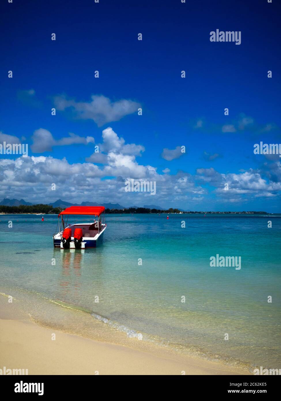 Speedboat moored in shallow waters by Mon Choisy beach, Mauritius ...