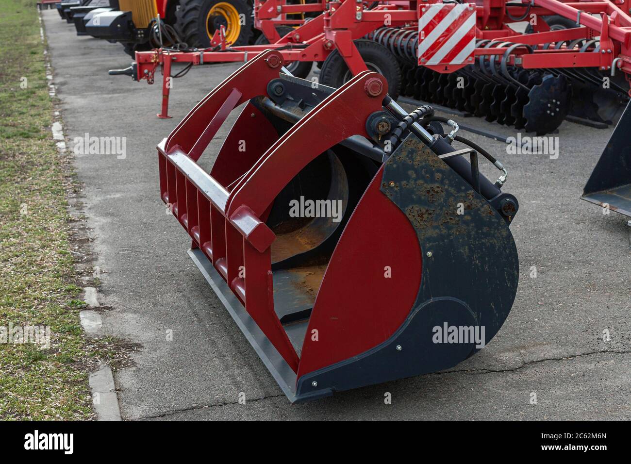 A large red bucket for agricultural machinery lies on the ground. Close ...
