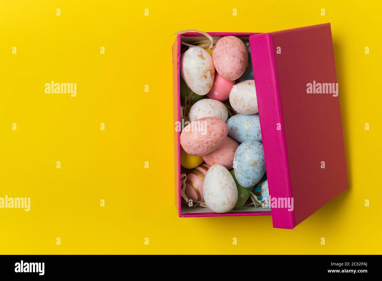 half open gift box with festive eggs on yellow background. Easter eggs ...