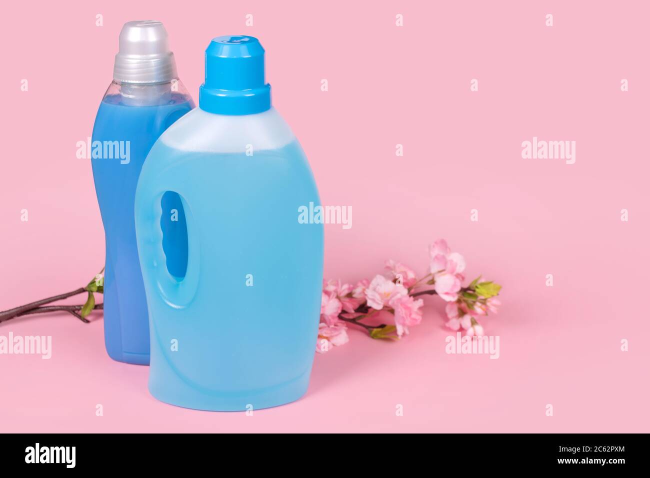Bottles of detergent and fabric softener on pink background with ...