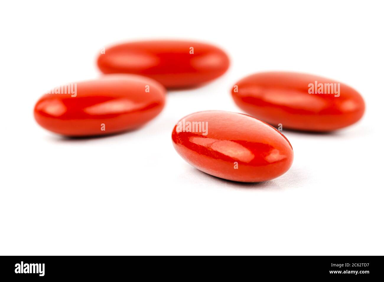 A macro shot of four red film-coated tablets arranged randomly ...