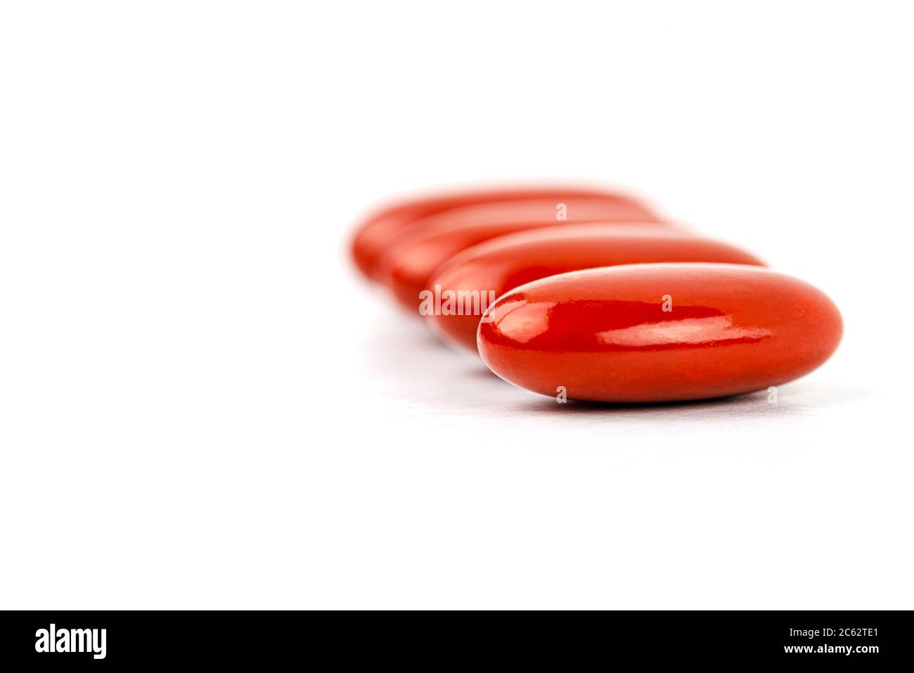 A macro shot of four red film-coated tablets arranged in a row ...