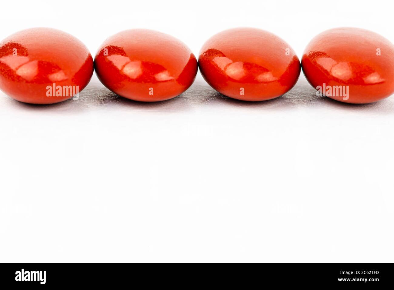 A macro shot of four red film-coated tablets arranged in a row on top ...