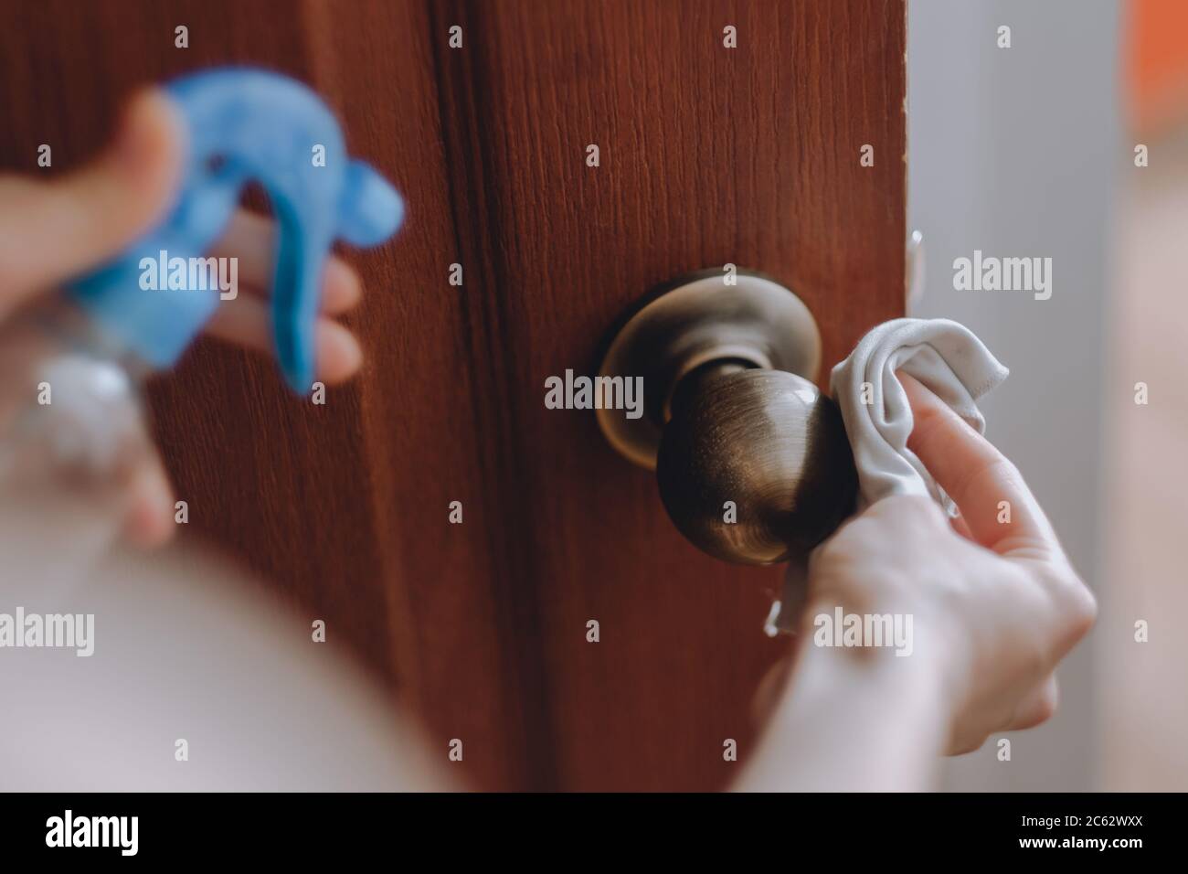 Woman cleans the door handle with an antibacterial spray Stock Photo ...