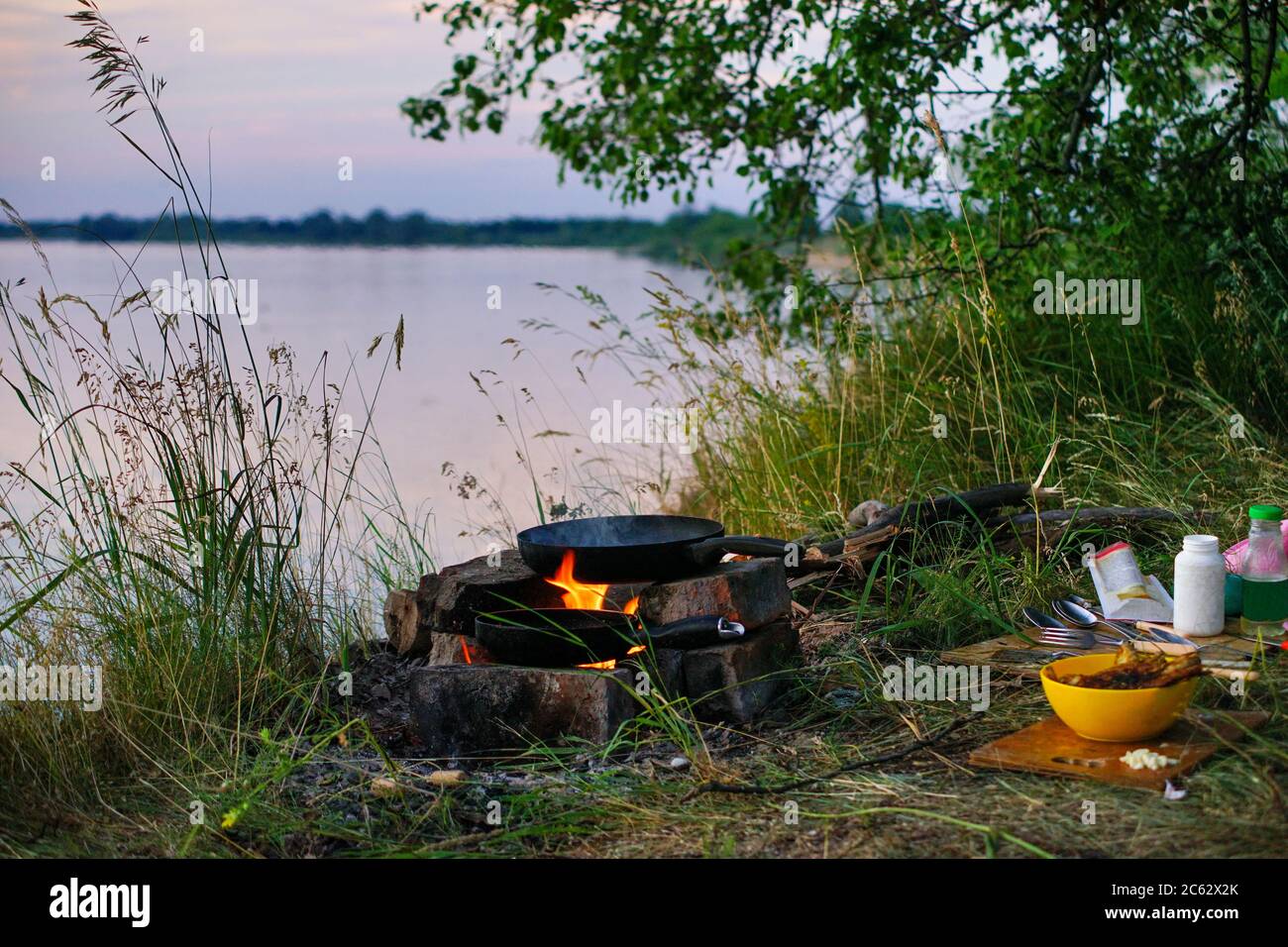 Fish in a pan is fried on a fire on the river bank. Dinner by the river ...